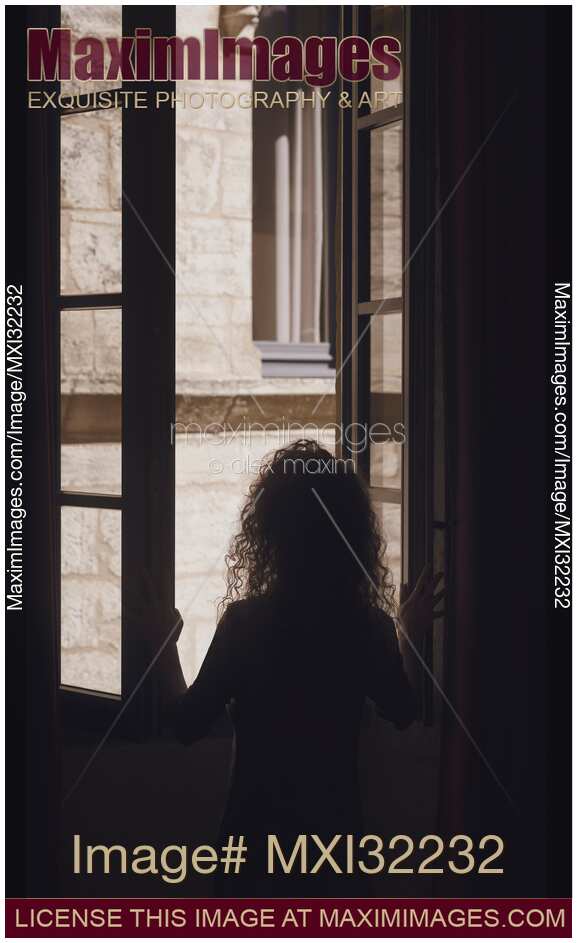Photo of Back of a woman looking out of an open window standing inside ...