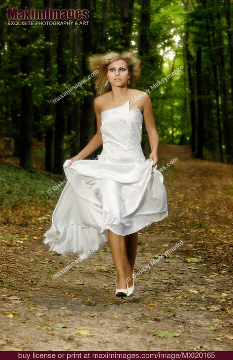 Runaway bride in wedding dress running through the woods. Stock Photo ...