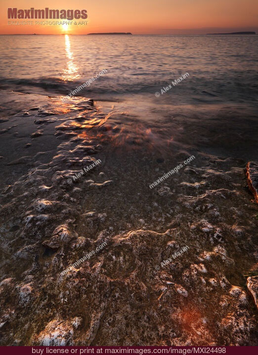 Sunset scenery of waves hitting rocks. Stock Photo MXI24498