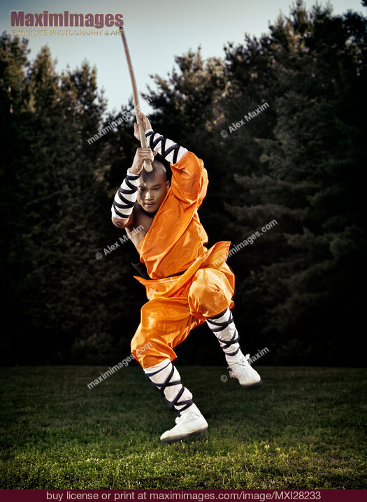 Shaolin warrior monk jumping with a staff. Stock Photo MXI28233