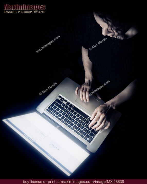 Woman face lit by the laptop screen light. Stock Photo MXI28836