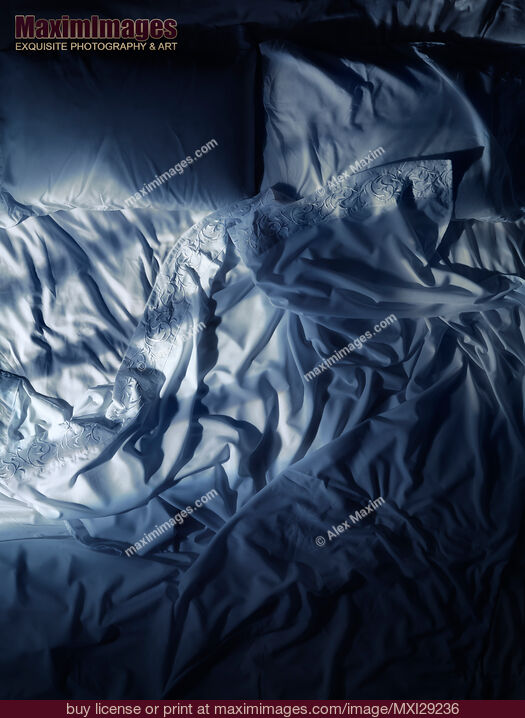 Unmade empty bed at night. Stock Photo MXI29236