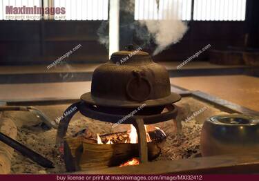 Japanese cast iron kettle steaming on fire in a sunken hearth Irori ...