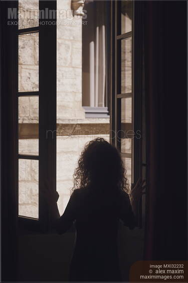 Photo of Back of a woman looking out of an open window standing inside ...