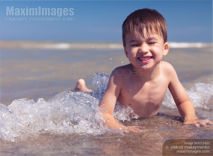 Photo of Cute happy child splashin in shallow water on the beach ...
