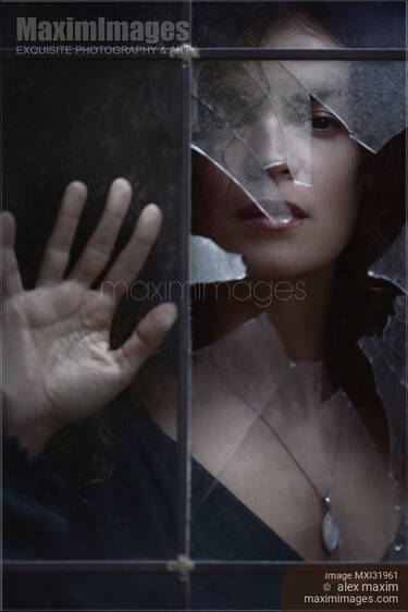 Photo of Dark moody portrait of woman face behind a broken window glass ...