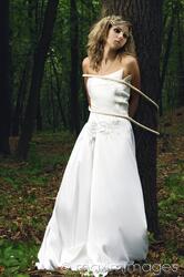 Photo of Young bride in wedding dress tied to a tree with ropes in a ...