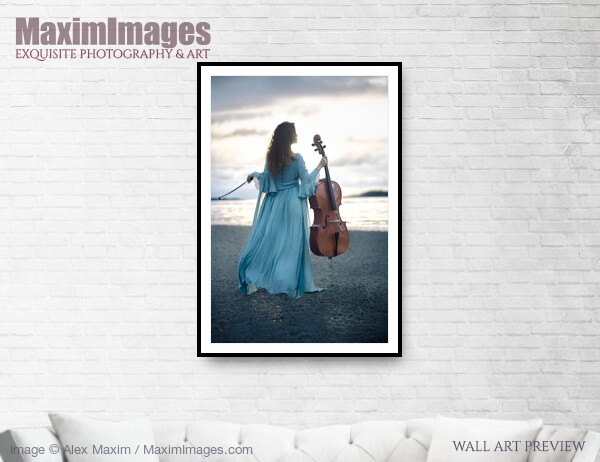 Art Print of Woman in blue dress standing on a sea shore holding a ...
